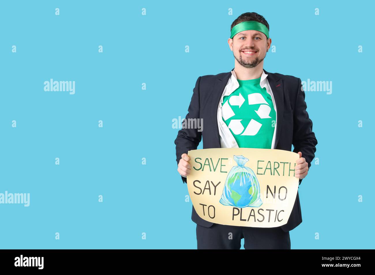 Young man dressed as eco superhero holding poster with text SAVE EARTH ...