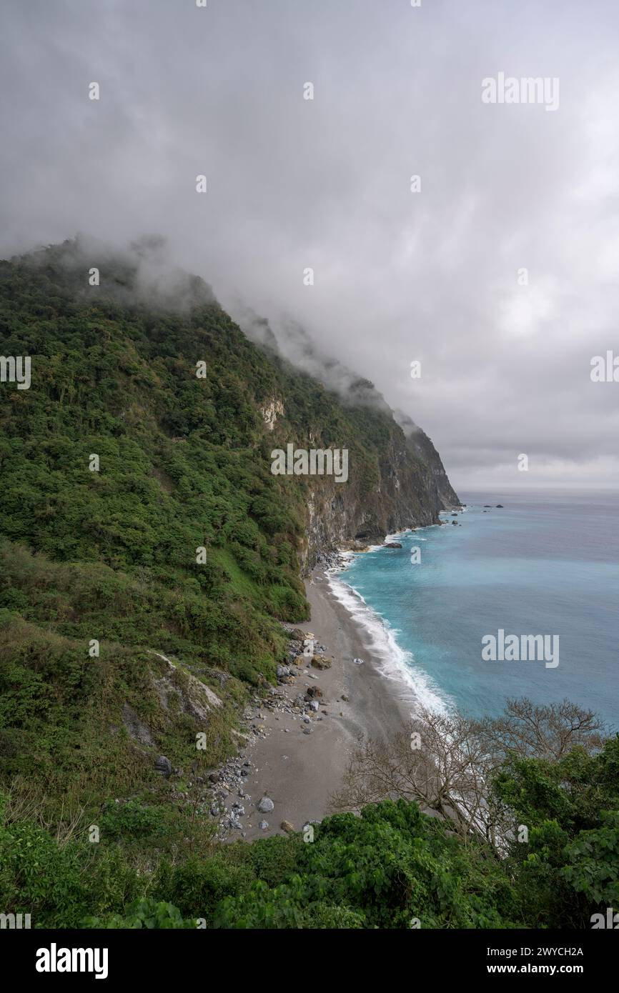 Majestic coastline with steep cliffs and turquoise ocean waves under a cloudy sky Stock Photo ...