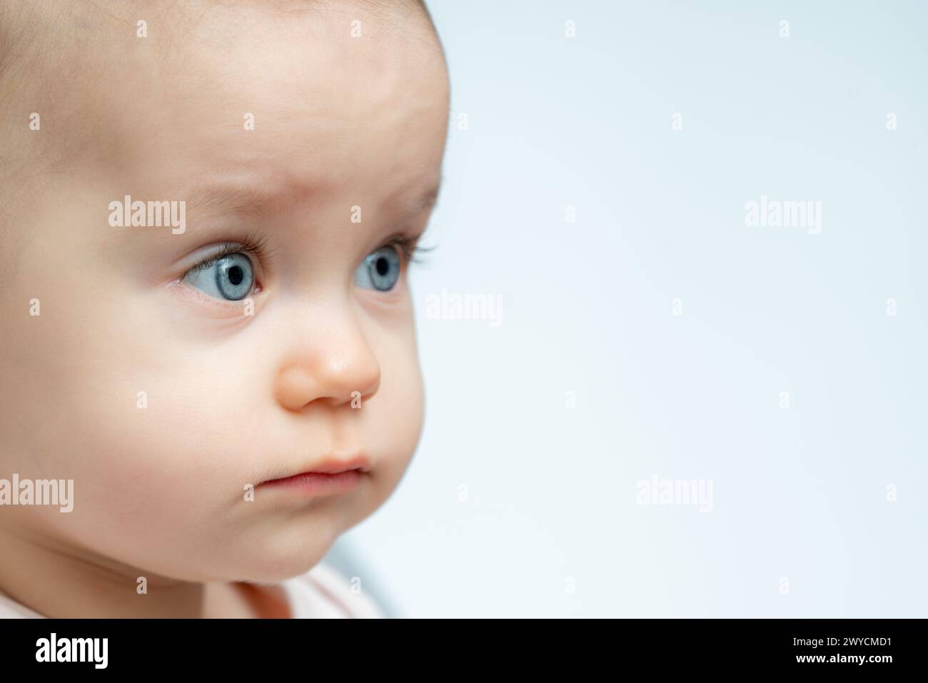 One year old baby gazes to the side with curious eyes. Concept of ...