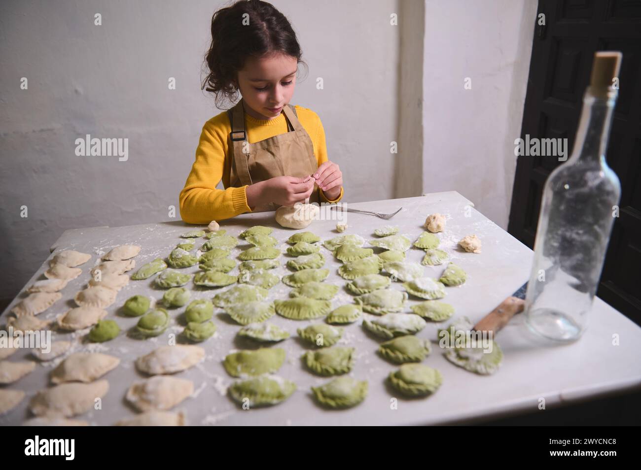 Cute little kid girl stuffing dough with mashed potatoes, modeling ...