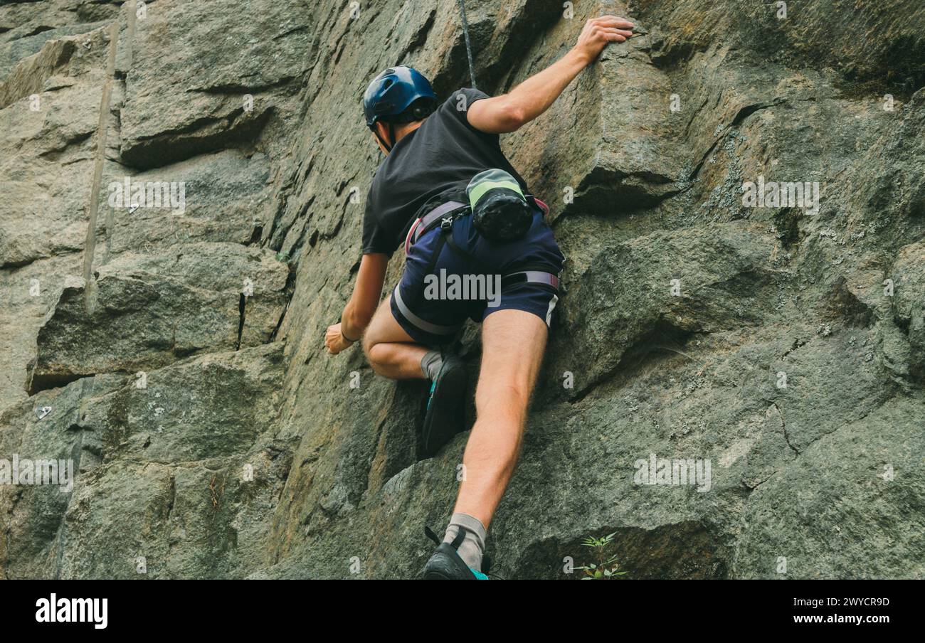 Young man in equipment doing rock climbing outdoors. Training area for ...