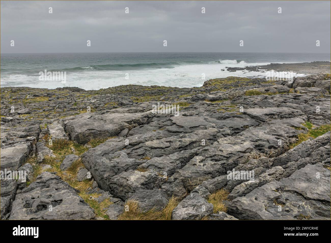 Limestone pavement leading down to a stormy sea with lichen and sea ...
