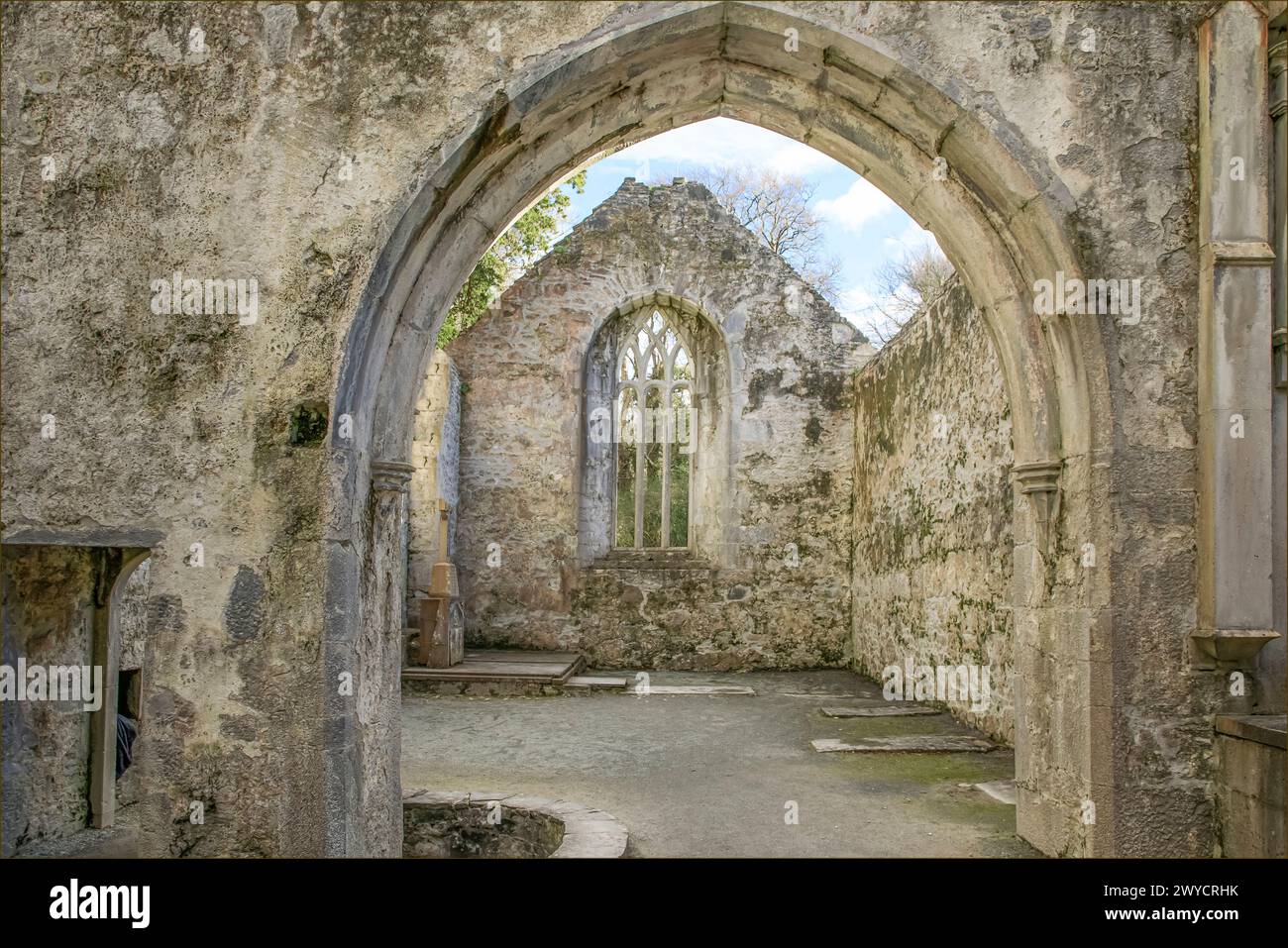 Looking through the archway of a derelict abbey made of light coloured ...