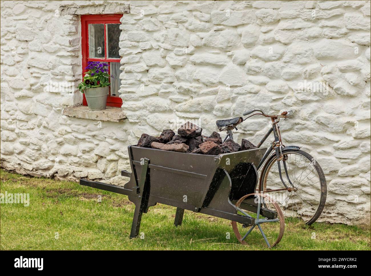 Wooden wheel barrow of peat outside a traditional iwhite painted rish ...