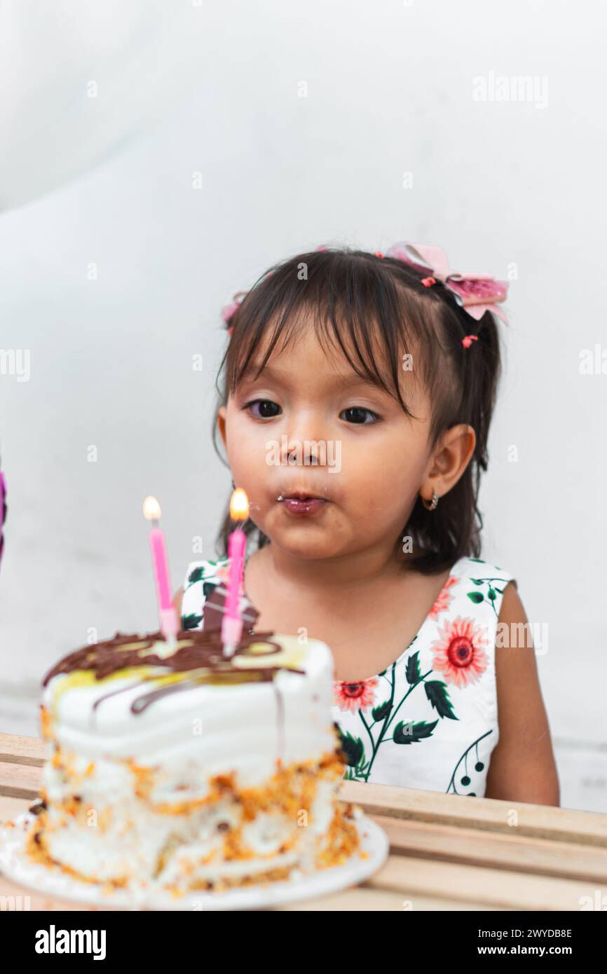little latina brunette girl trying to blow out the candles that are on ...