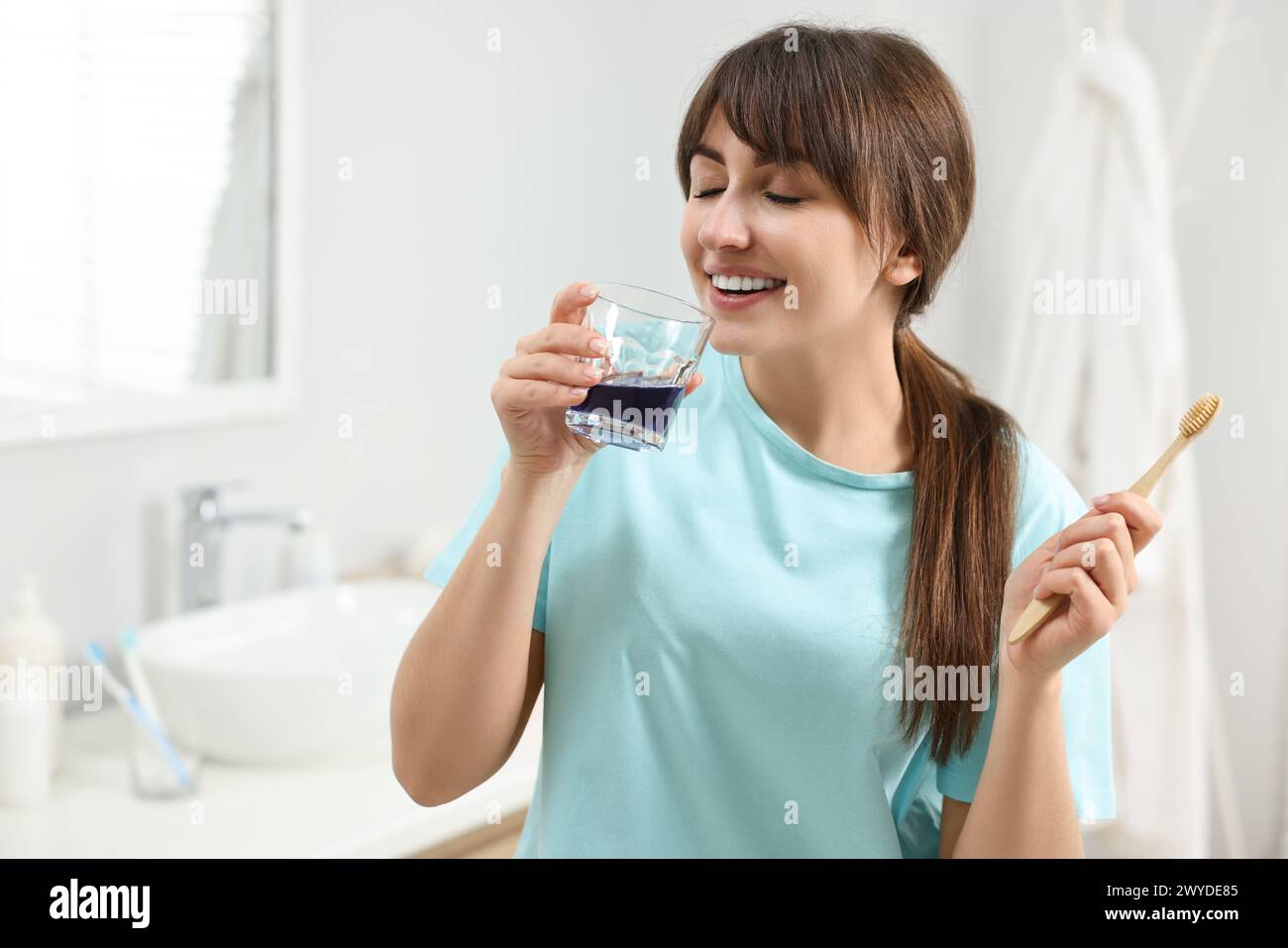 Young woman using mouthwash in bathroom. Oral hygiene Stock Photo - Alamy