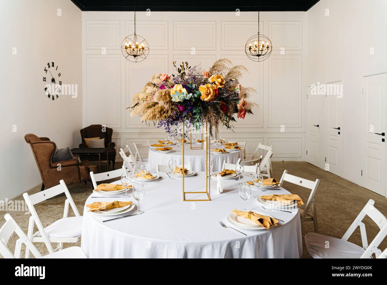 A sophisticated dining table arrangement with gold accents and a lavish floral centerpiece in an ...