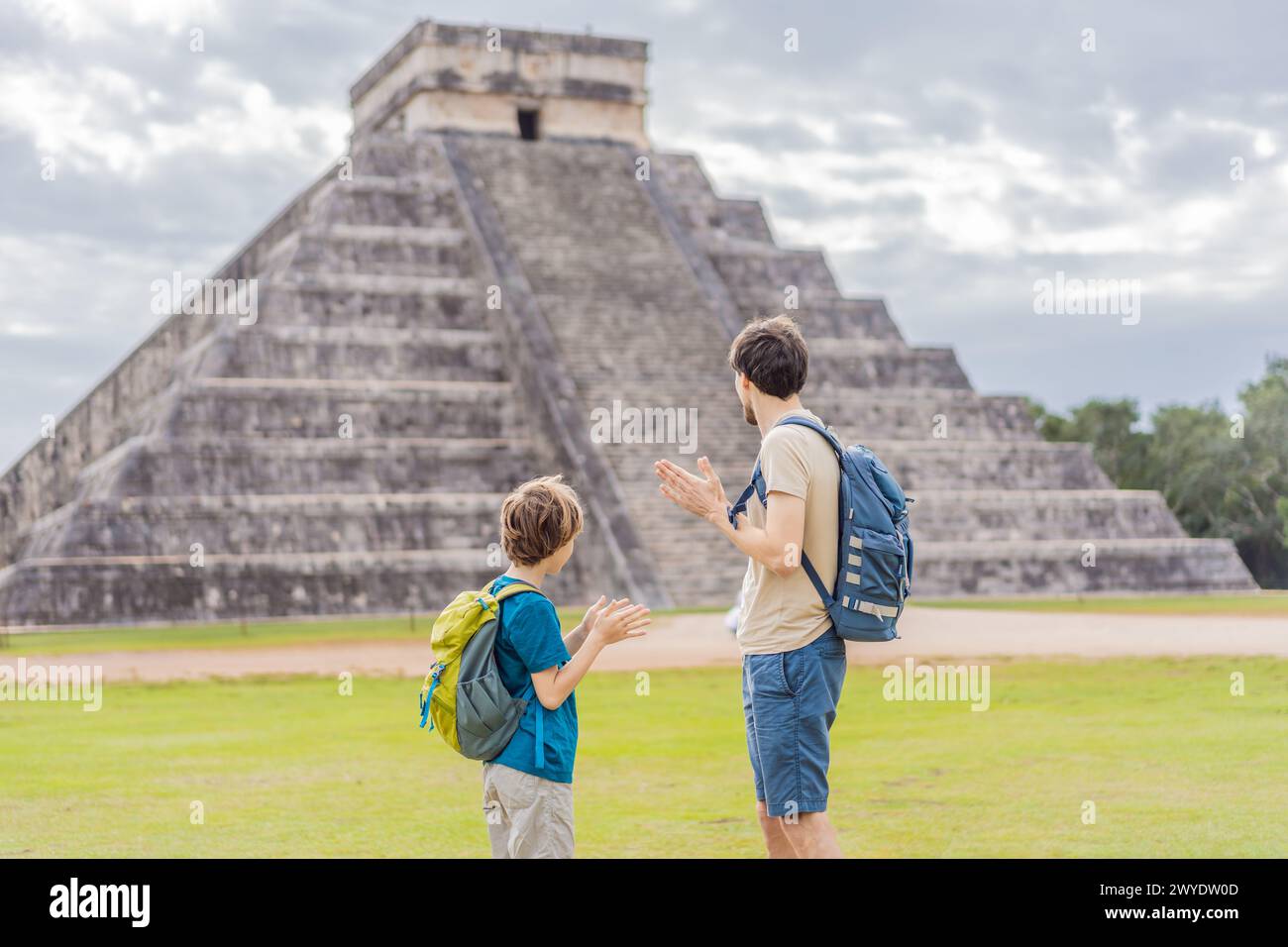 Father and son tourists observing the old pyramid and temple of the ...