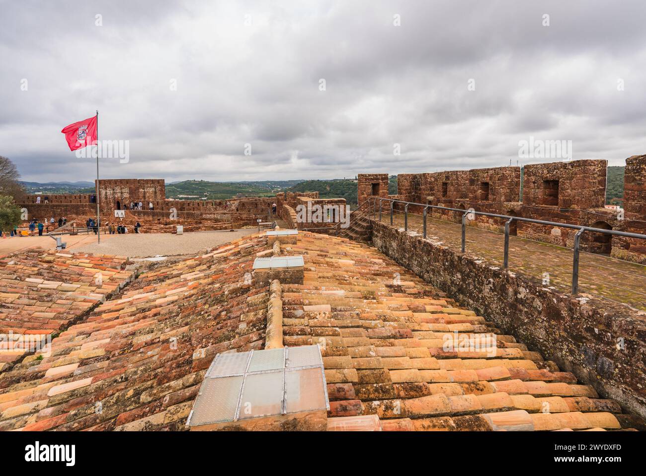 Terracotta-tiled rooftops of Silves Castle with the Portuguese flag ...