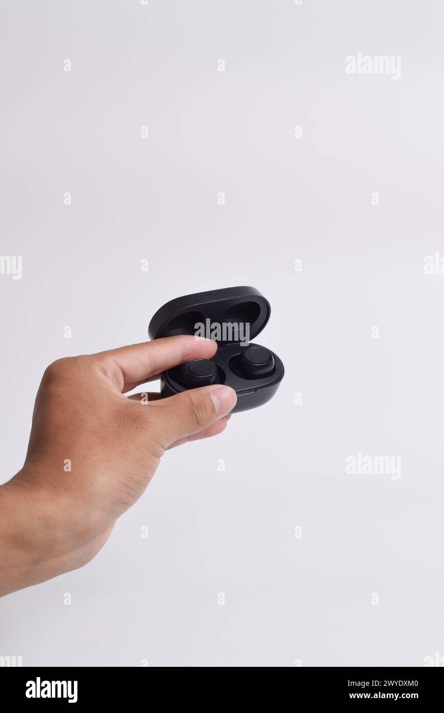 Hand holding Headphones wireless earphones with charging case isolated ...