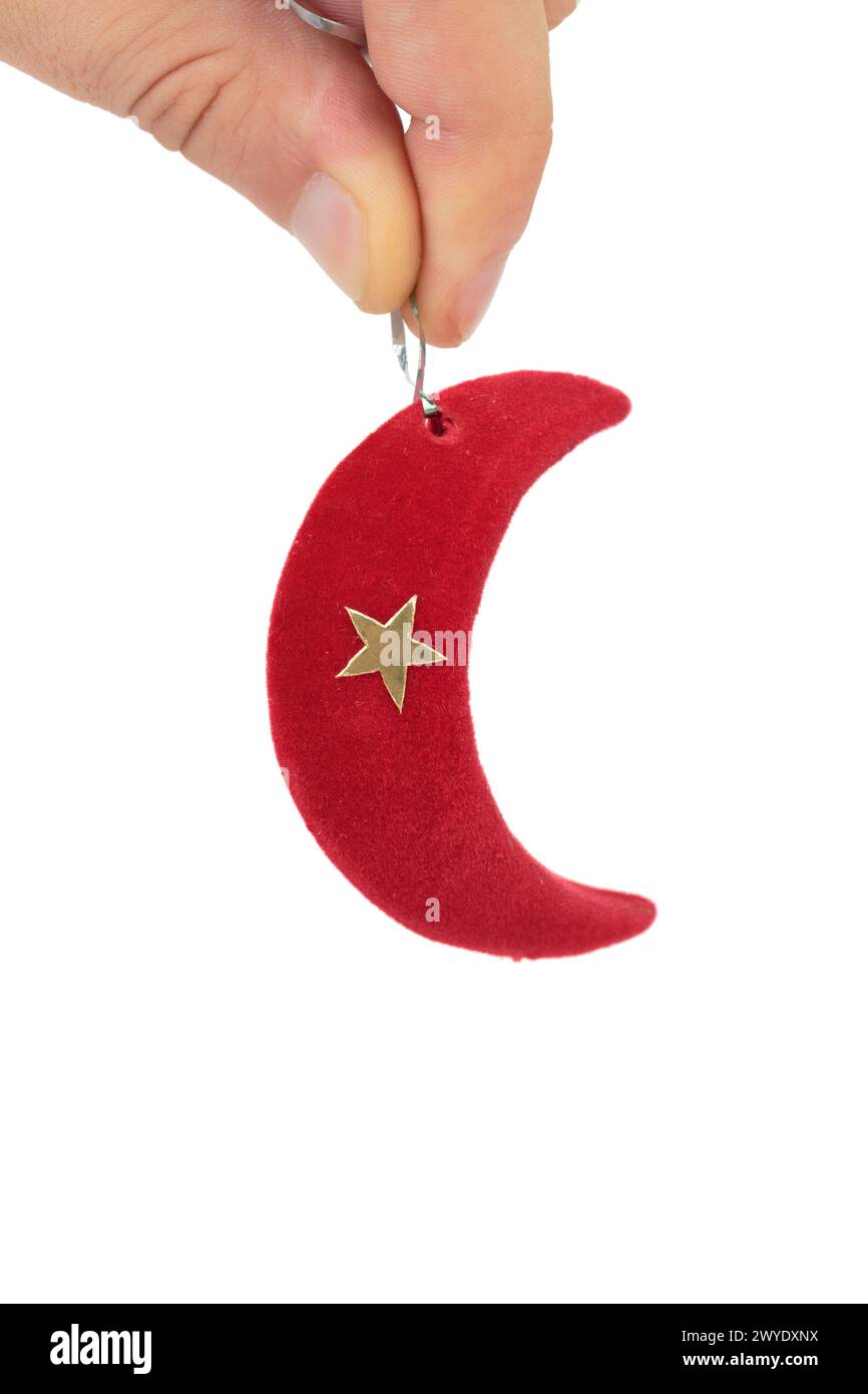 The hand holds a Christmas toy in the shape of a crescent moon ...