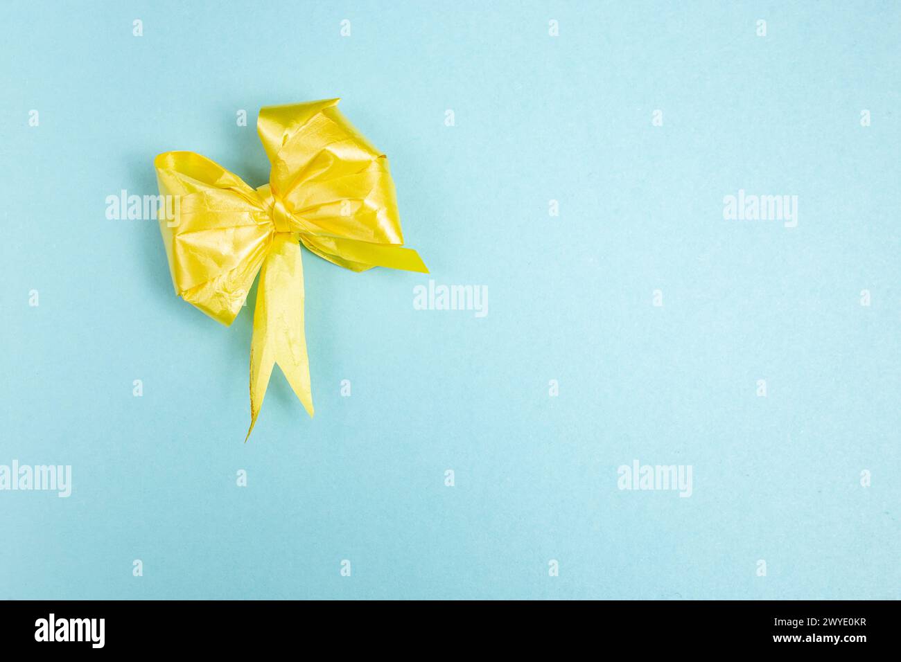 yellow crumpled ribbon on blue background, minimal greeting card Stock ...
