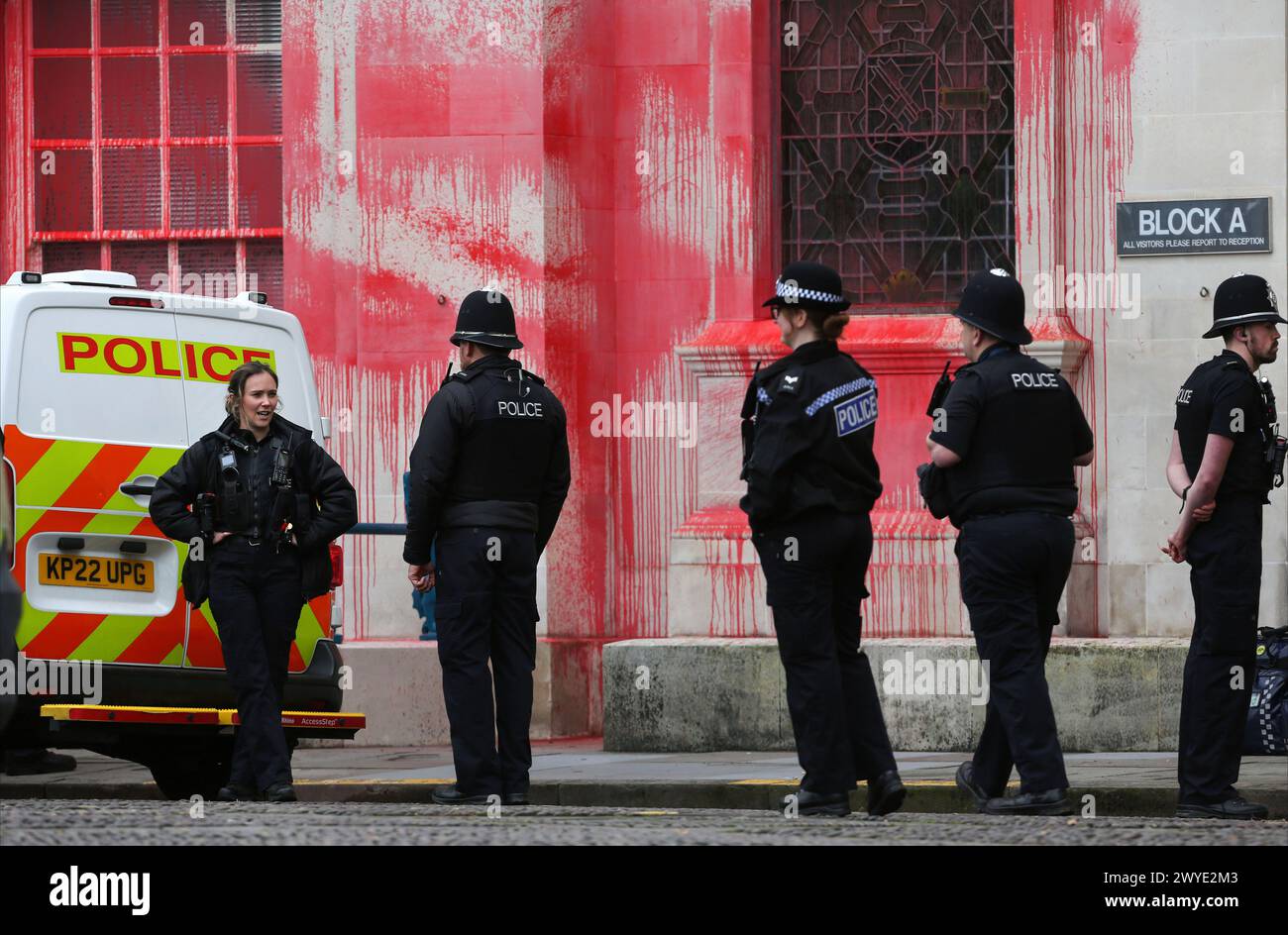 Police officers stand outside county hall, with its exterior splashed ...