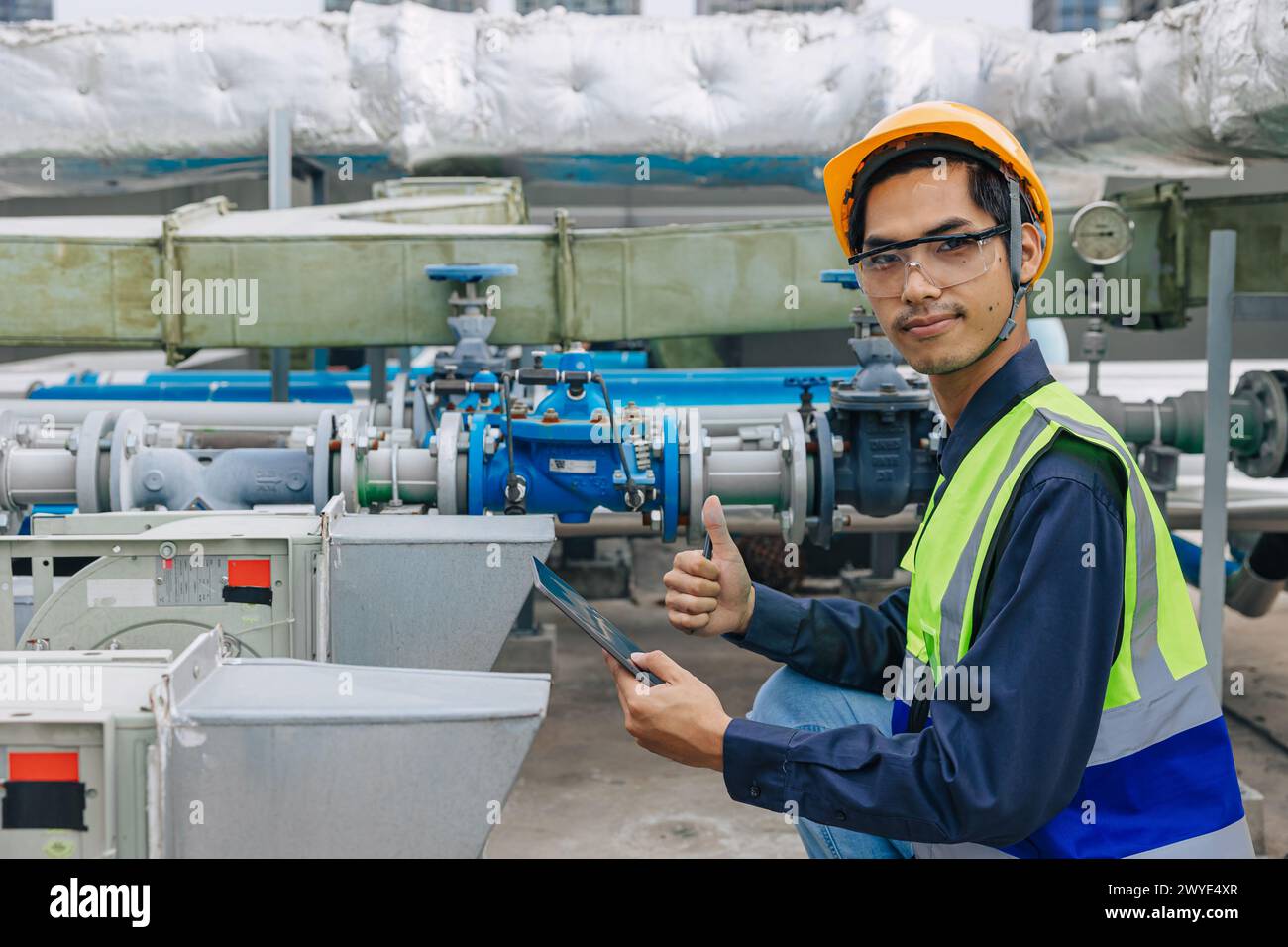 young engineer male in reflective vest is giving a thumbs up work pipe ...