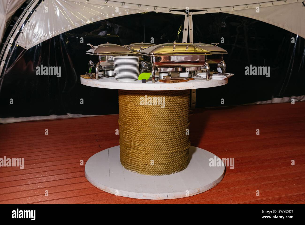 A buffet table featuring chafing dishes and stacks of plates ready for ...