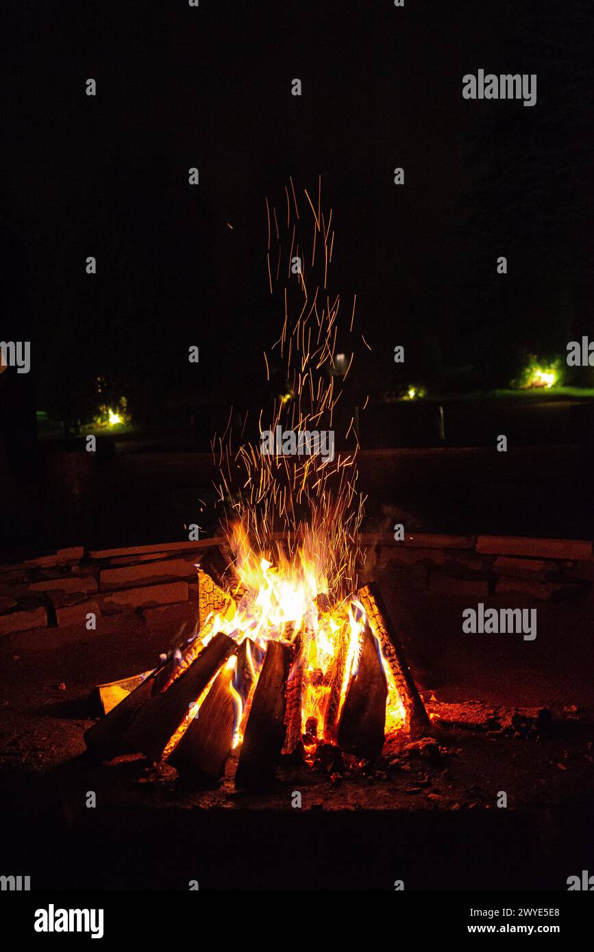 The dynamic energy of a campfire at night is captured, with bright ...