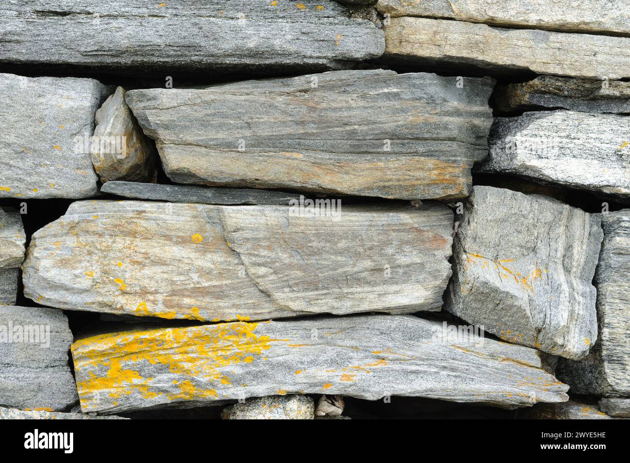 A detailed view of a dry stone wall with interlocking gray stones and ...