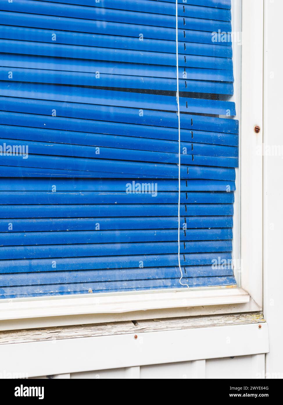 A window featuring a blue roller shade covering it, partially blocking ...