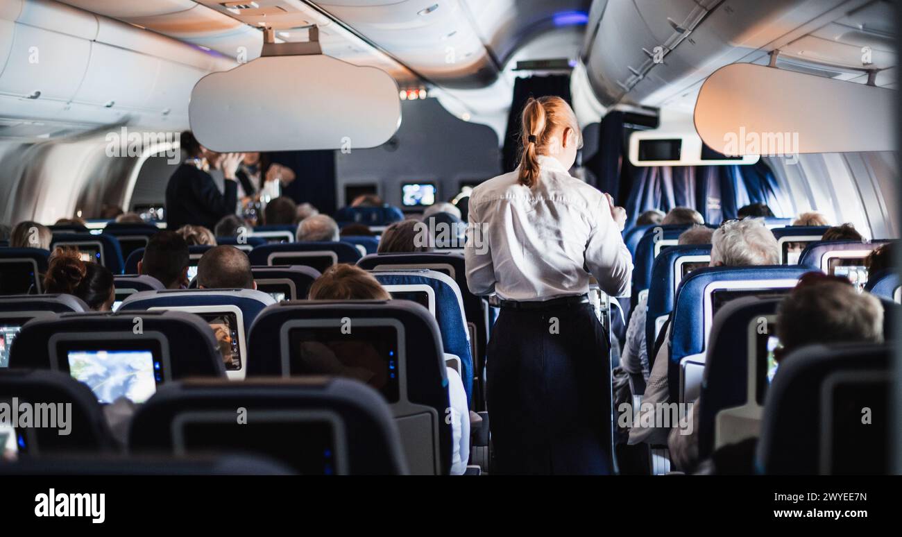 Interior of airplane with passengers on seats and stewardess in uniform ...