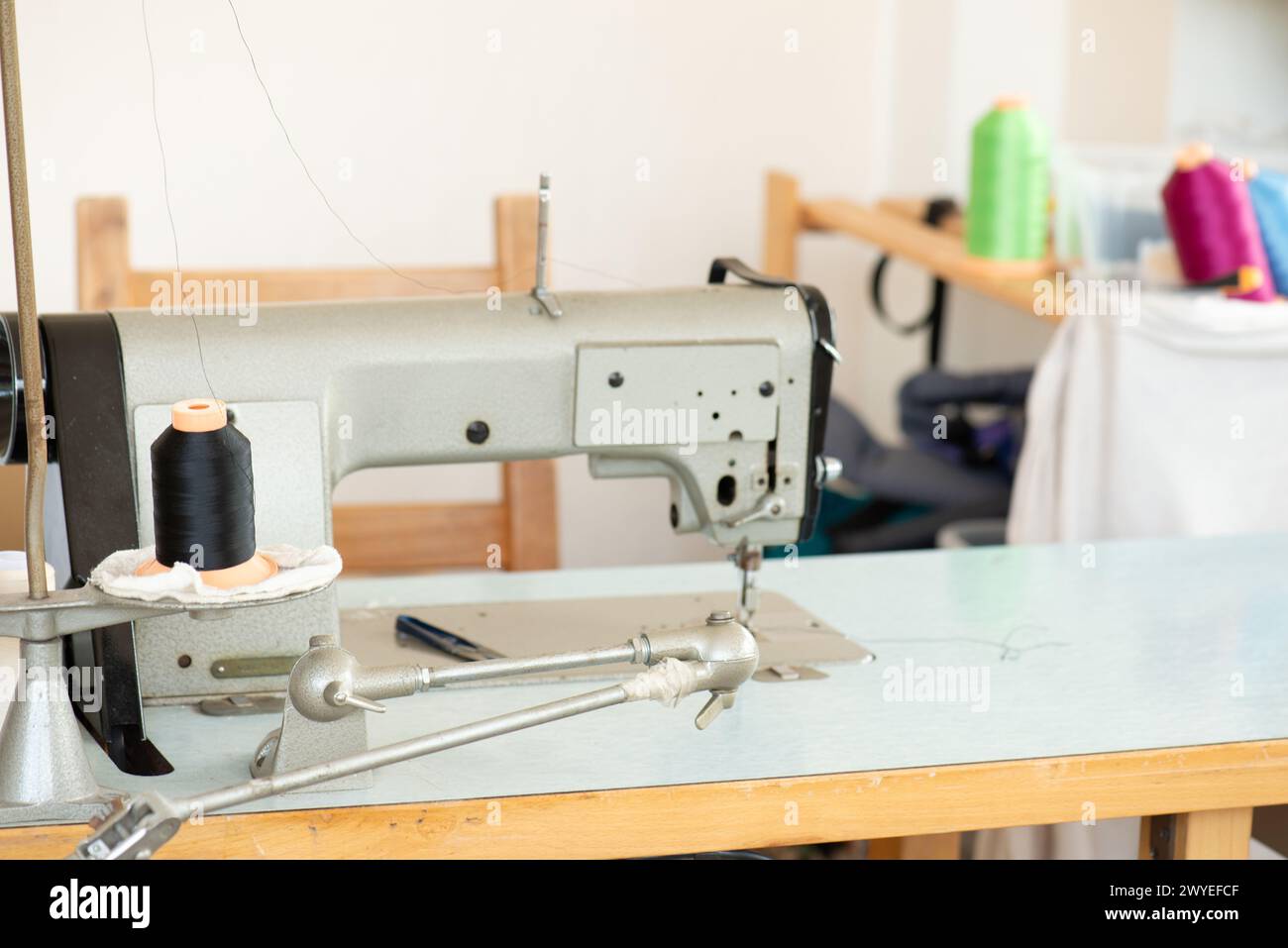 Industrial sewing machine with colorful thread, working place ...