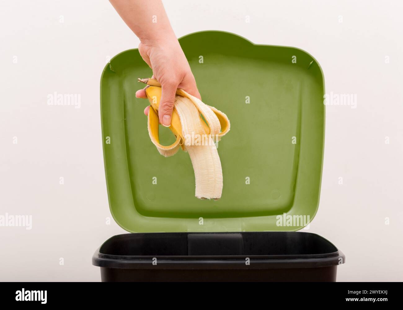 Close-up of a person throwing a half-finished banana into the bin ...
