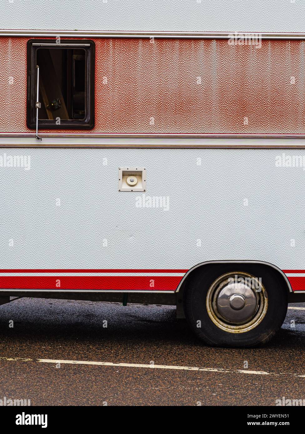 A white and red Camping Caravan is parked on the side of the road in a ...