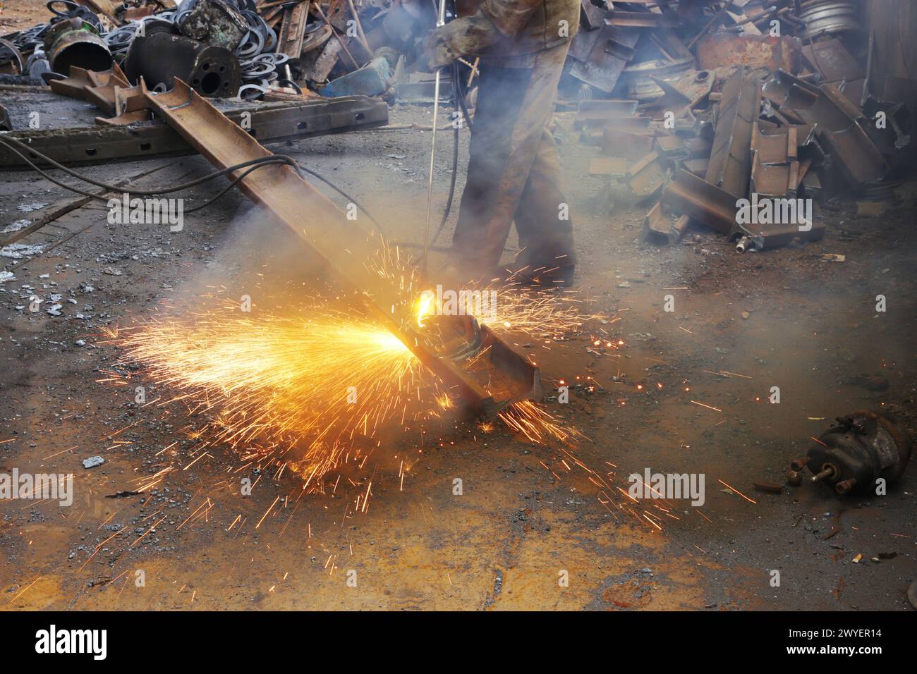 A worker recycles an old, rusty iron rail using an autogen, cutting ...