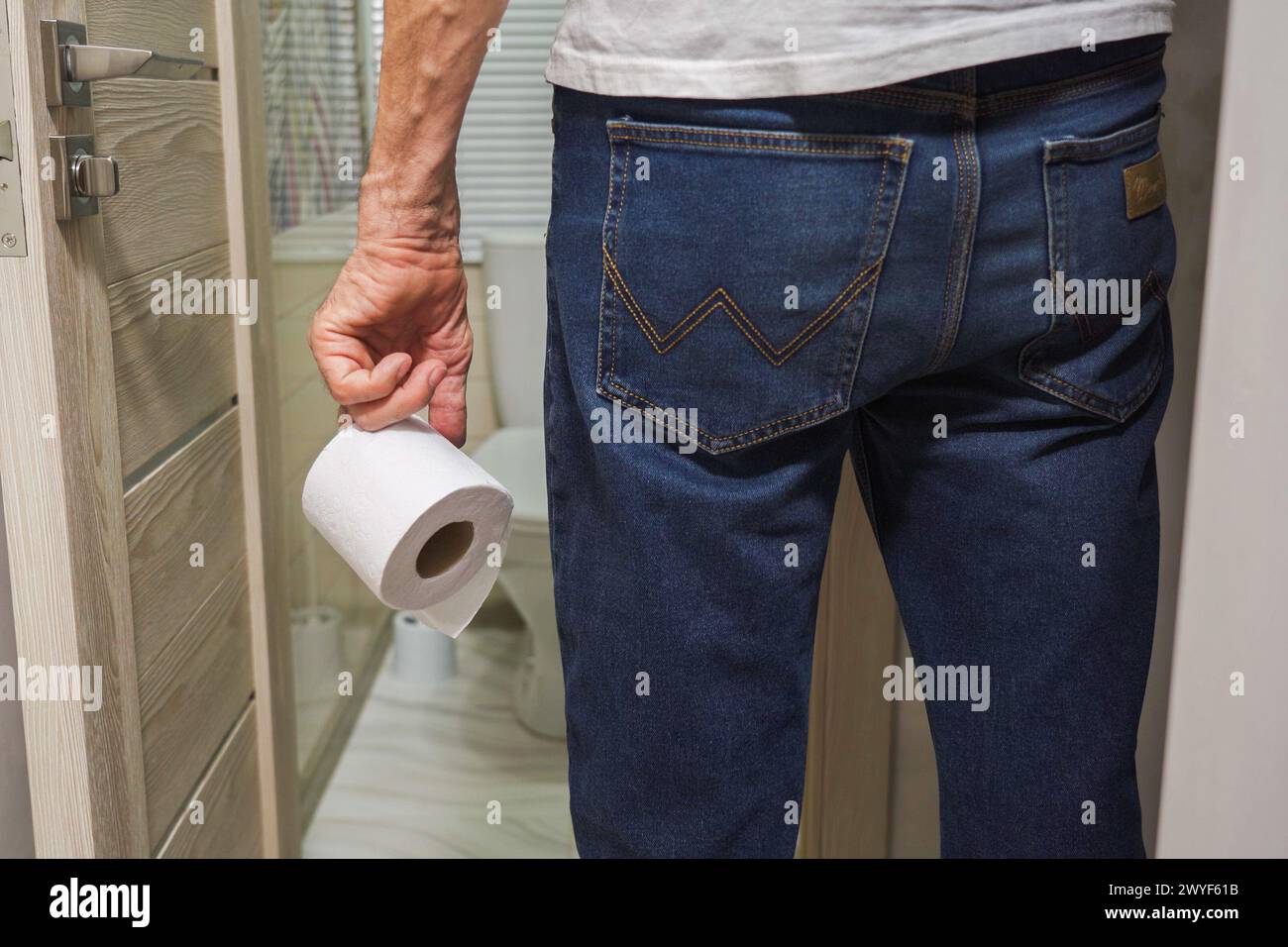 An older man's hand holding a roll of toilet paper in front of the ...