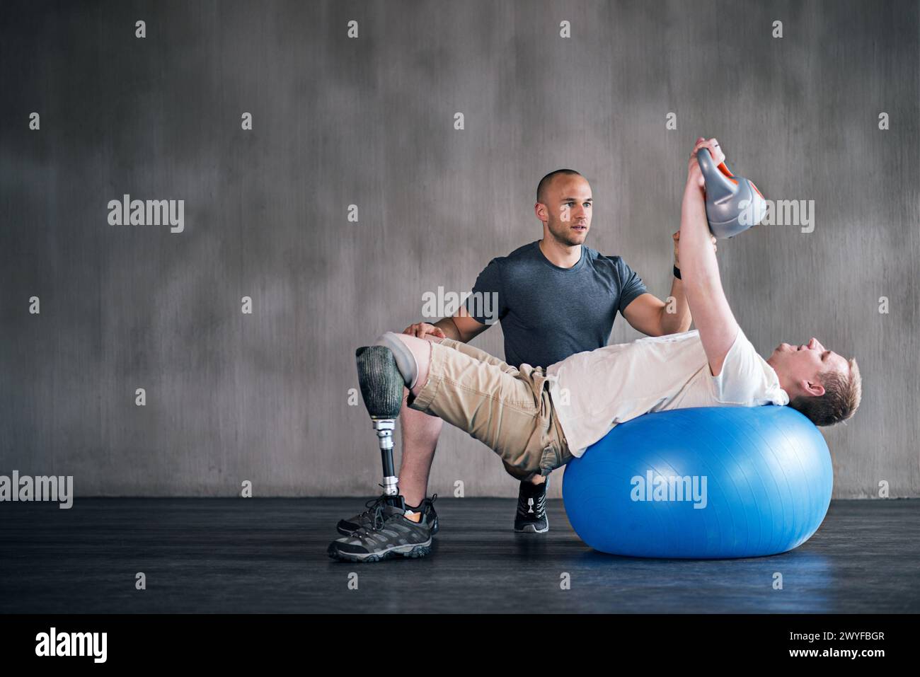 Trainer, person with a disability and prosthetic leg and dumbbell in physiotherapy, studio and ...