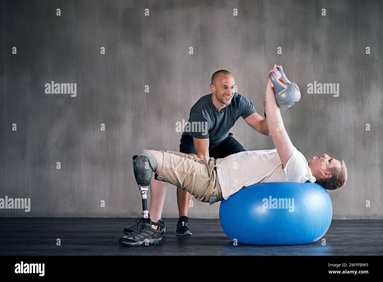 Trainer, man with a disability and prosthetic leg and dumbbell in physiotherapy, studio and gym ...