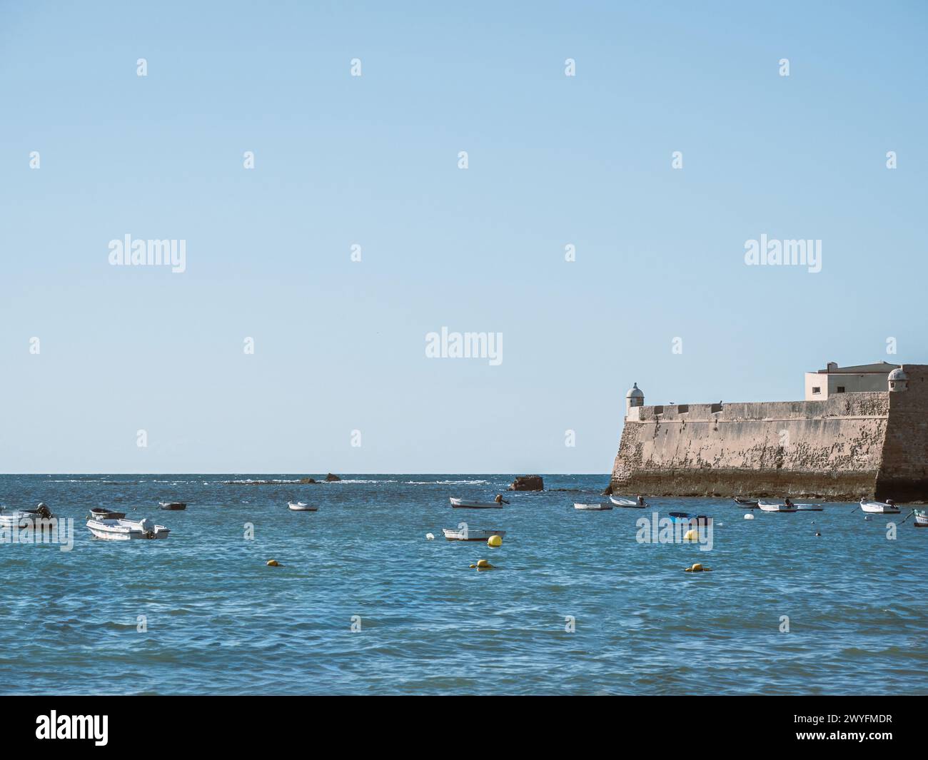 Boats anchored next to the walls of the fort of Santa Catalina in Cadiz ...