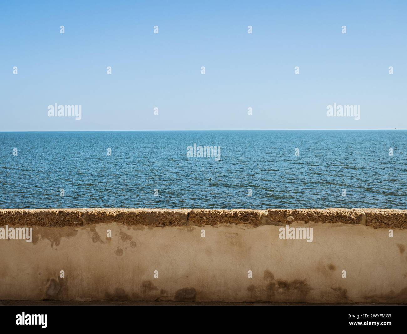 Empty sea horizon view over a stone wall waterfront of the seaside ...