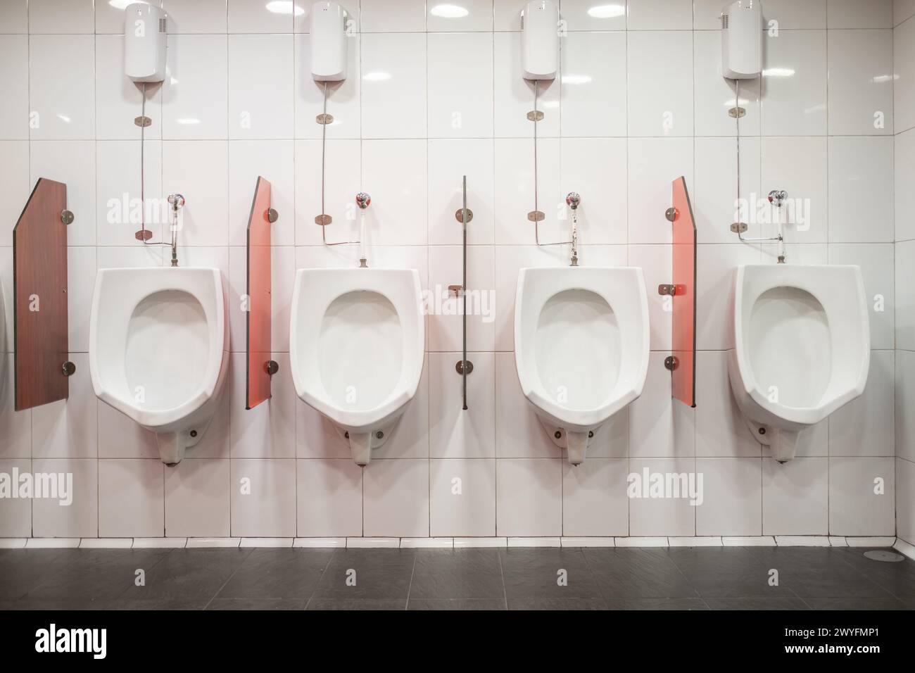 Front view of a white-walled public restroom with four symmetrical ...