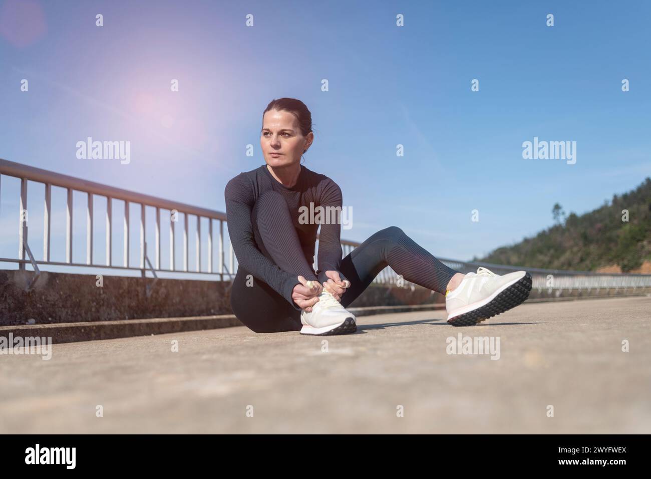 Sporty female runner tying her shoelaces in preparation for running and ...