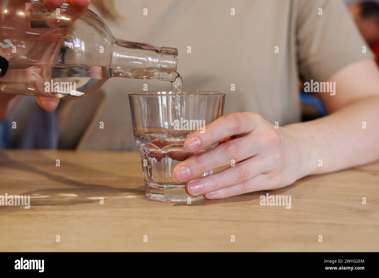 Hand pouring water from bottle into glass at wooden table Stock Photo ...