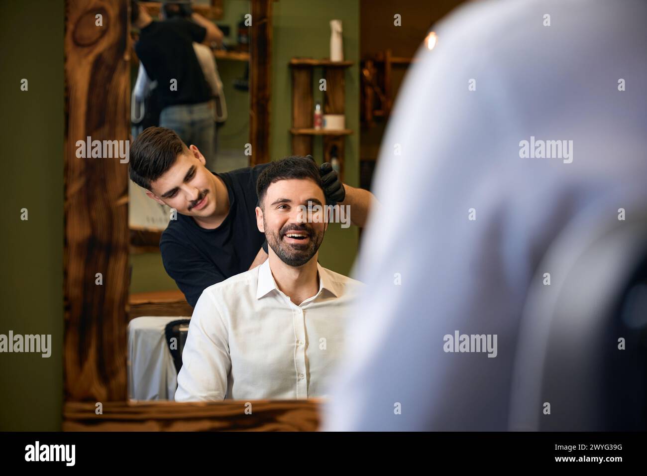 Barber using scissors to style hair for his client in barbershop Stock ...