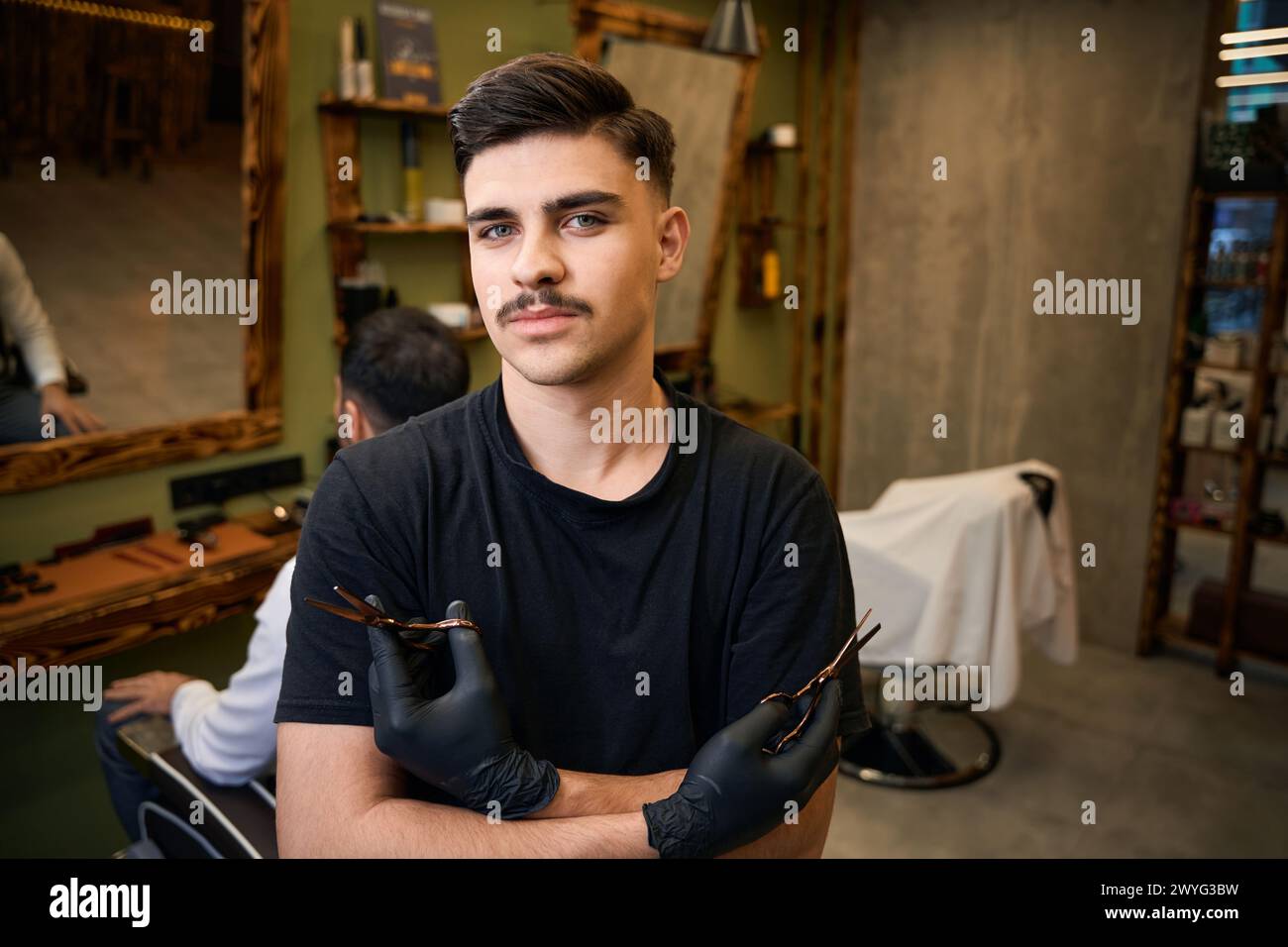 Barber standing with crossed arms holding scissors in barbershop Stock ...
