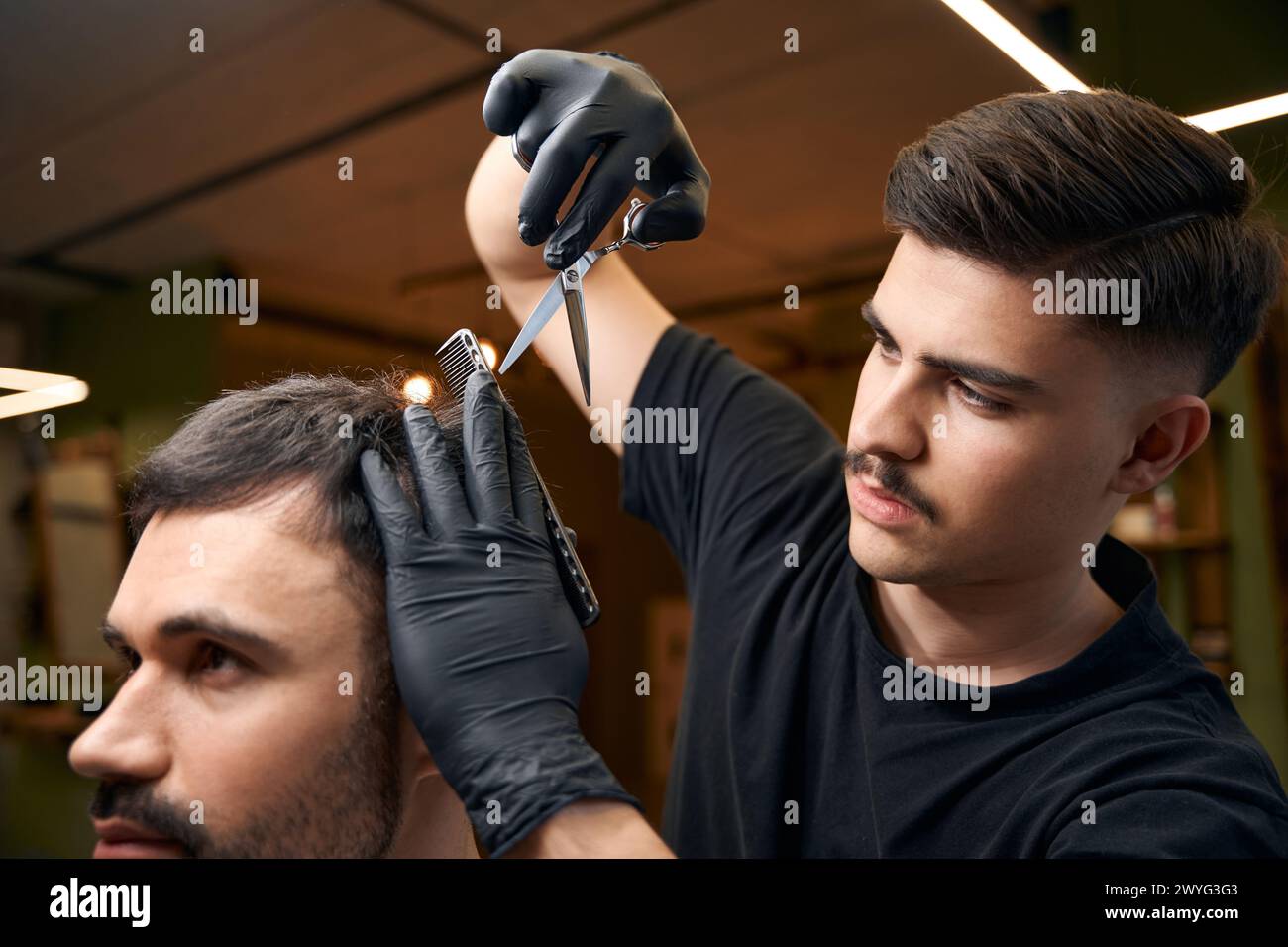 Barber using scissors to style hair for his client in barbershop Stock ...