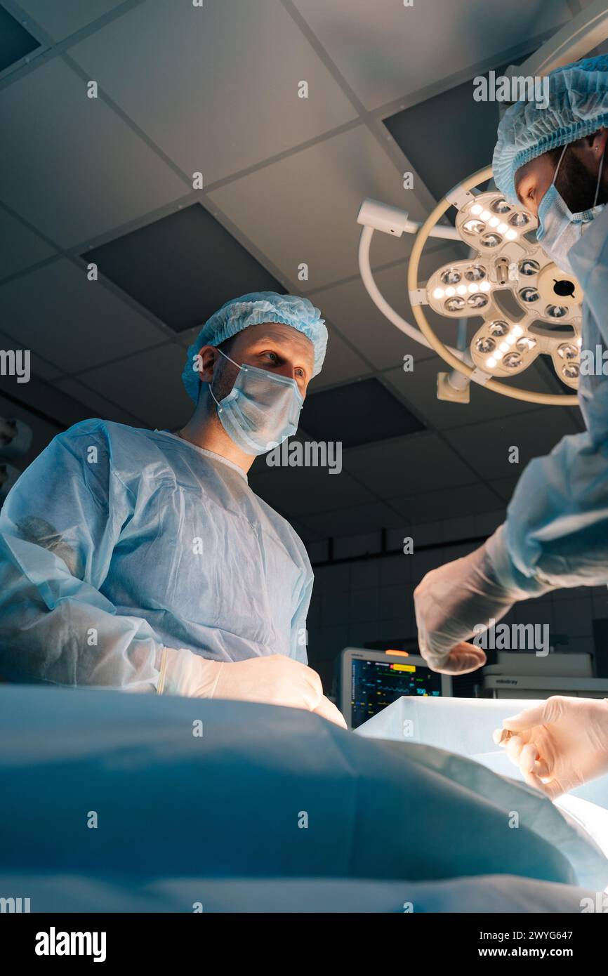 Low-angle view portrait of surgery professional operating patient. Male ...