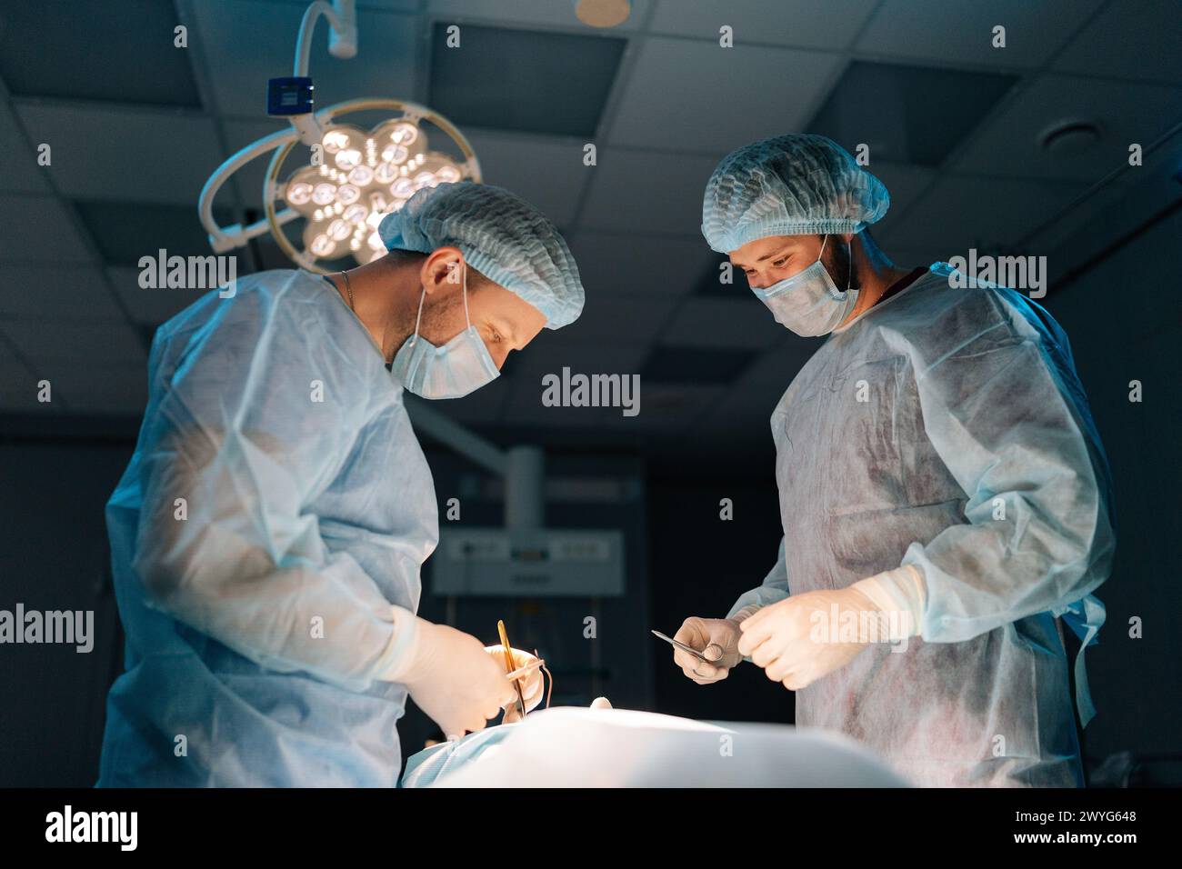 Low-angle view of surgery professionals operating patient. Male doctors ...
