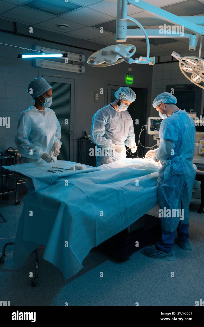 Vertical shot of multiethnic surgeons and nurses in uniform performing ...