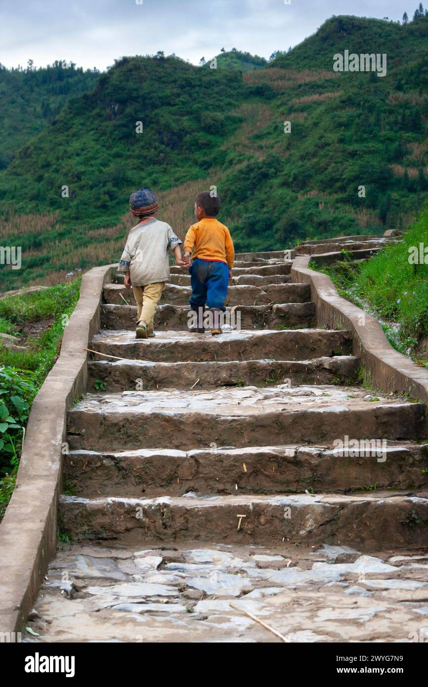 Two young boys from a hilltribe village walking hand in hand near Sapa ...