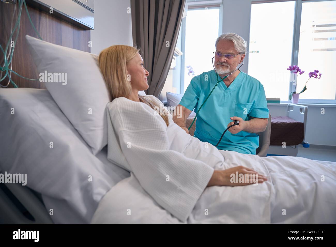 Physician performing physical examination of inpatient during ward ...