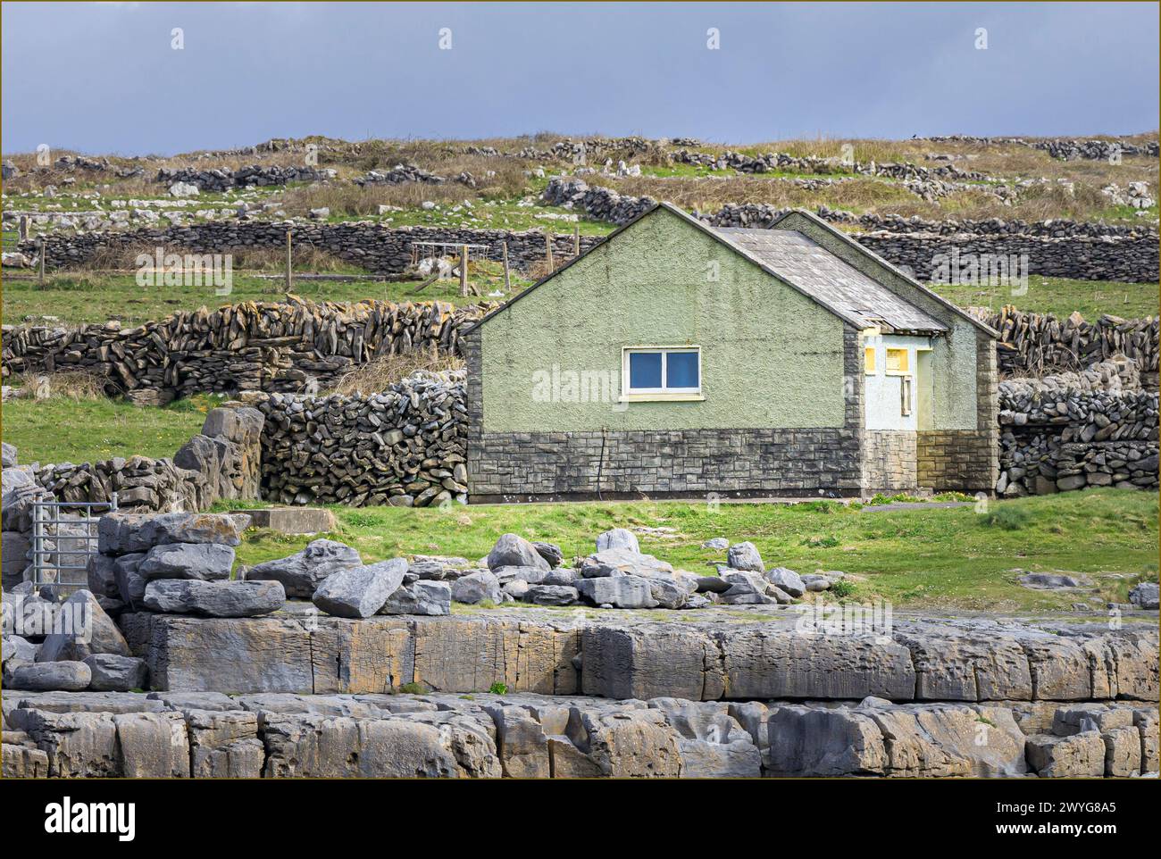 Small green painted building in a series of limestone walls and with a ...