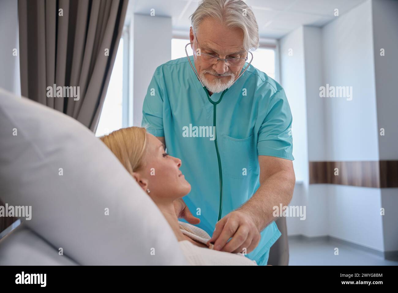 Attending doctor performing cardiac auscultation of inpatient during ...