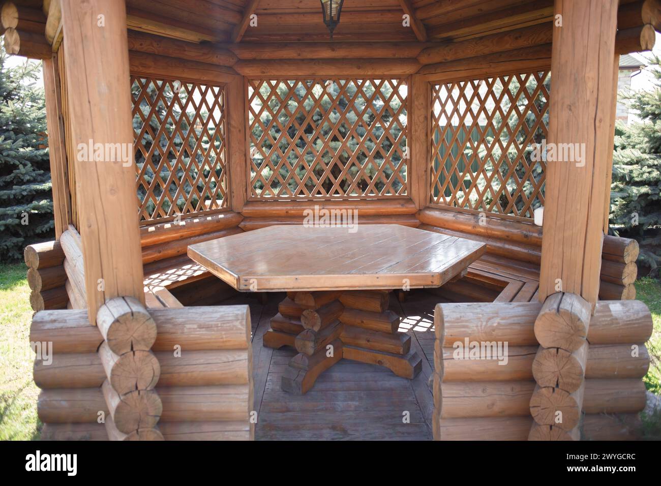 White gazebo or pavilion with a wooden table, benches and a flower ...