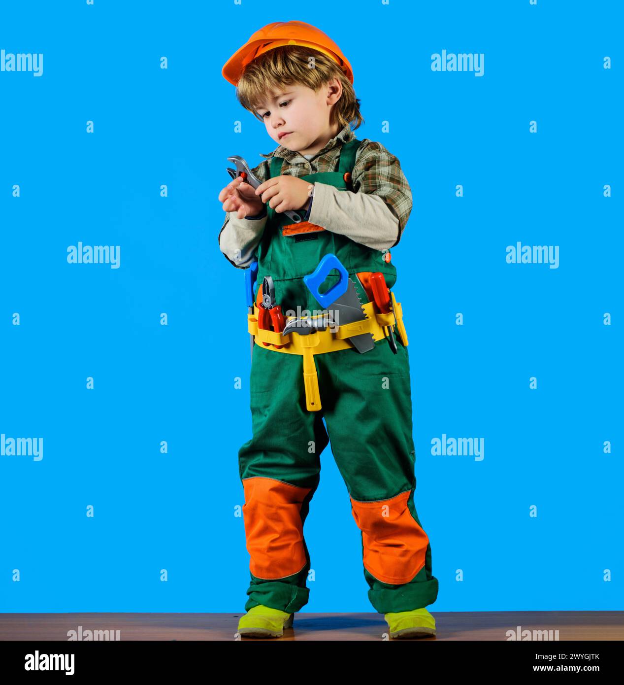 Little builder in helmet and tool belt with adjustable wrench. Kid ...