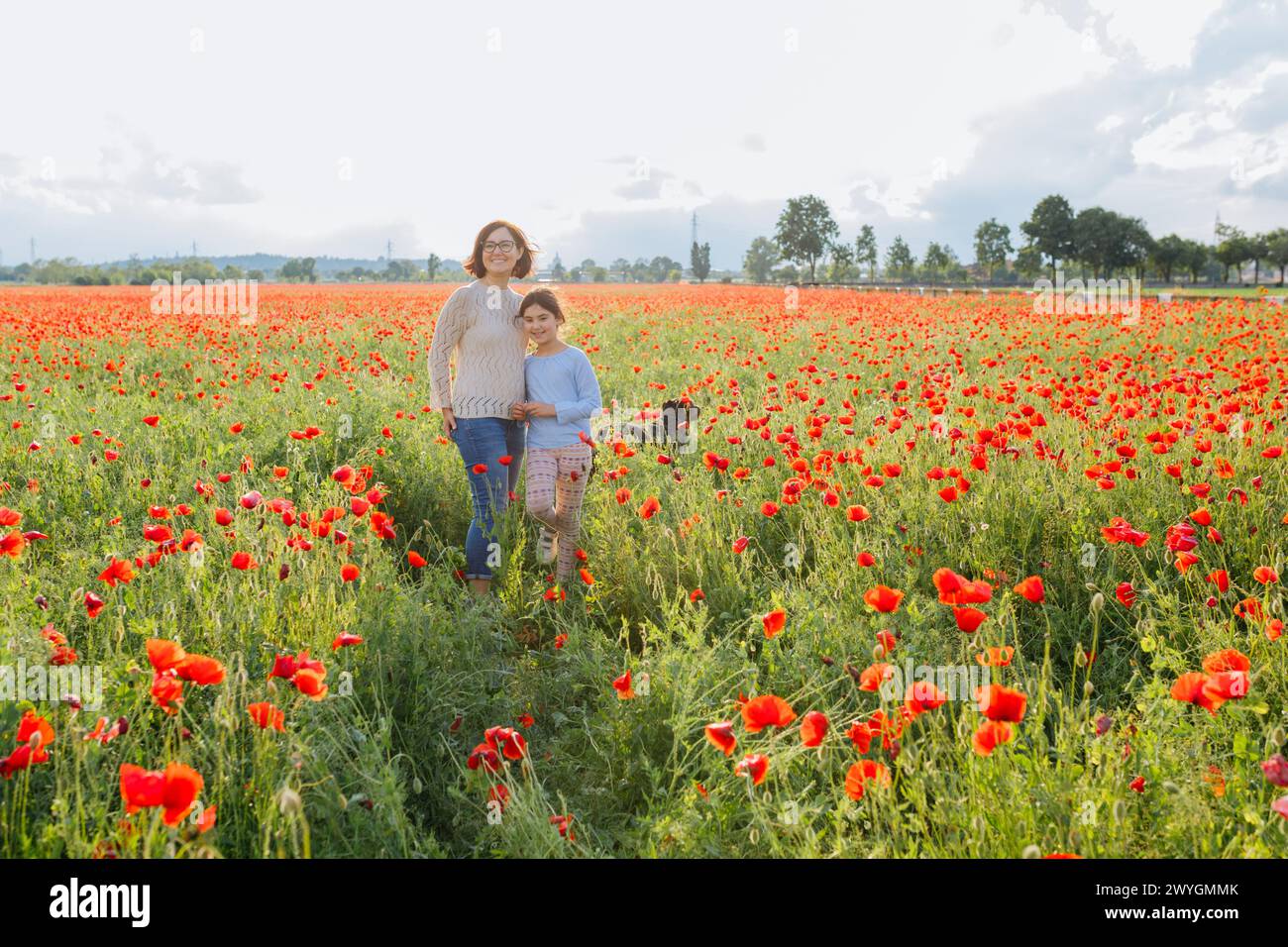 woman and her child standing in the poppy field next to their running ...