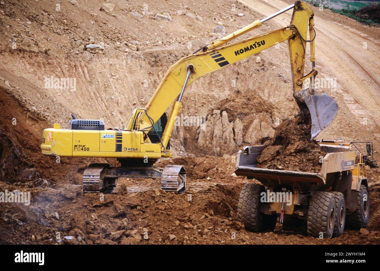 Excavator at construction site, loading truck Stock Photo - Alamy