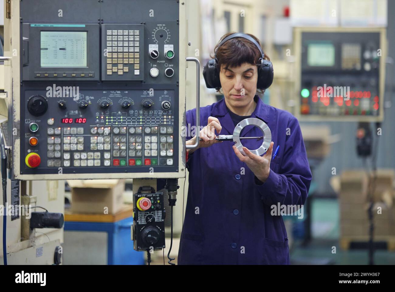 Worker measuring with caliper. Area automated CNC lathes. Machined ...